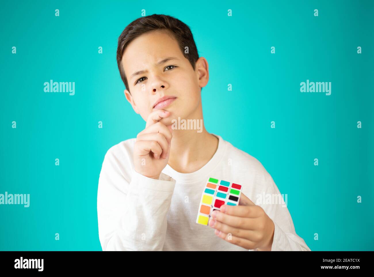 Young boy pensive plays with rubik's cube over green background Stock ...