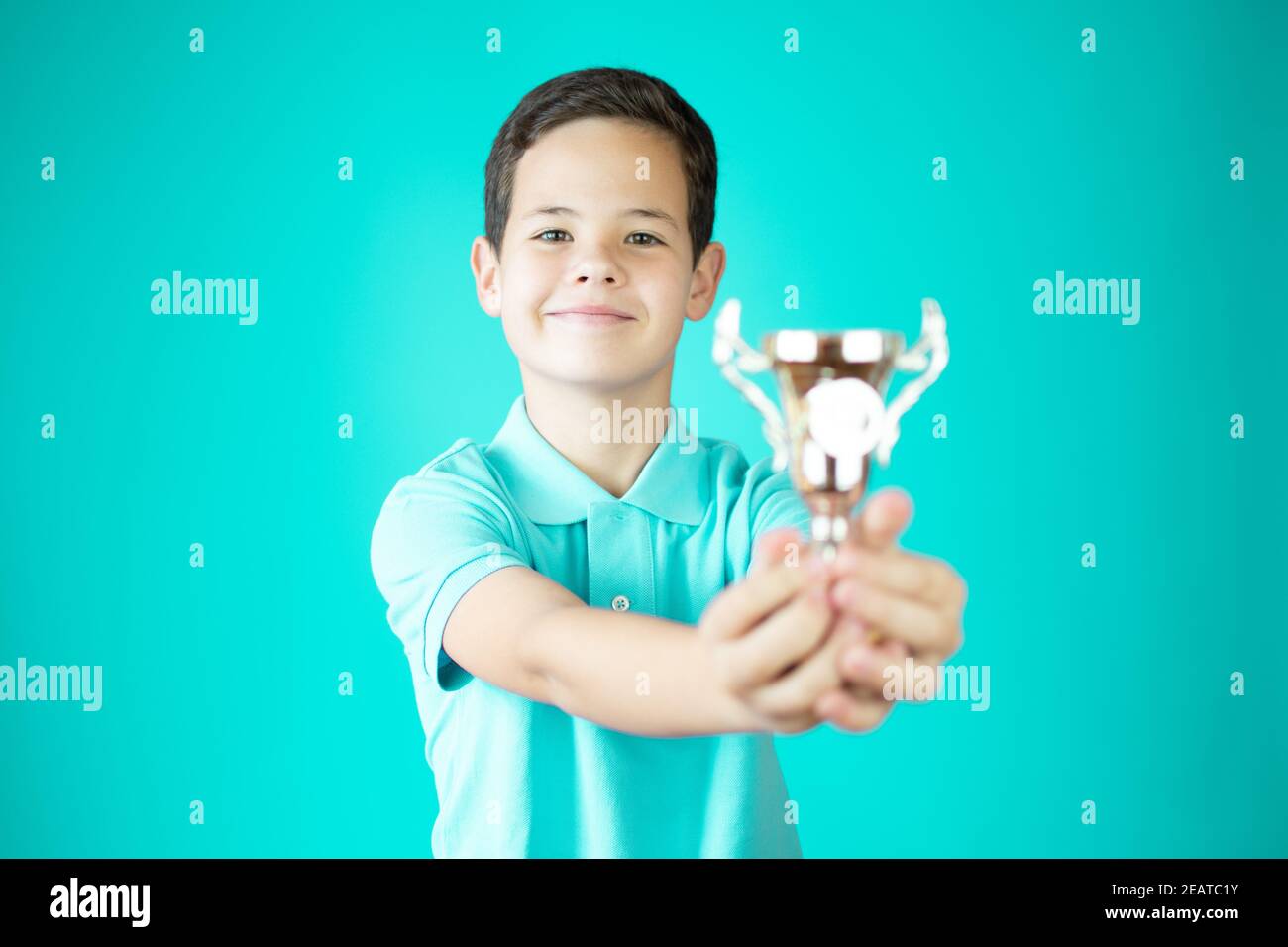young boy holding a trophy with celebrating pose over green background ...