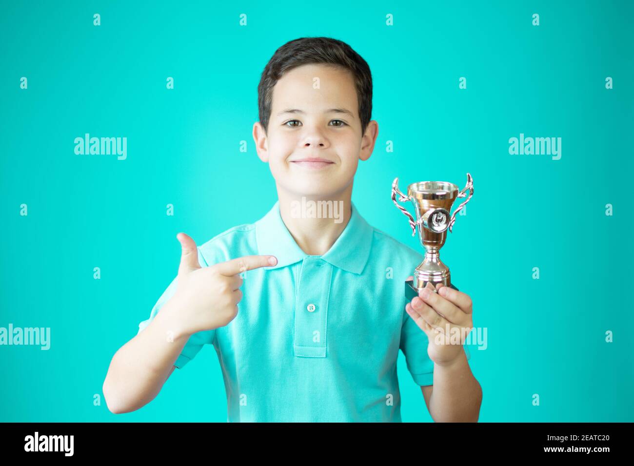 young boy holding a trophy with celebrating pose over green background ...