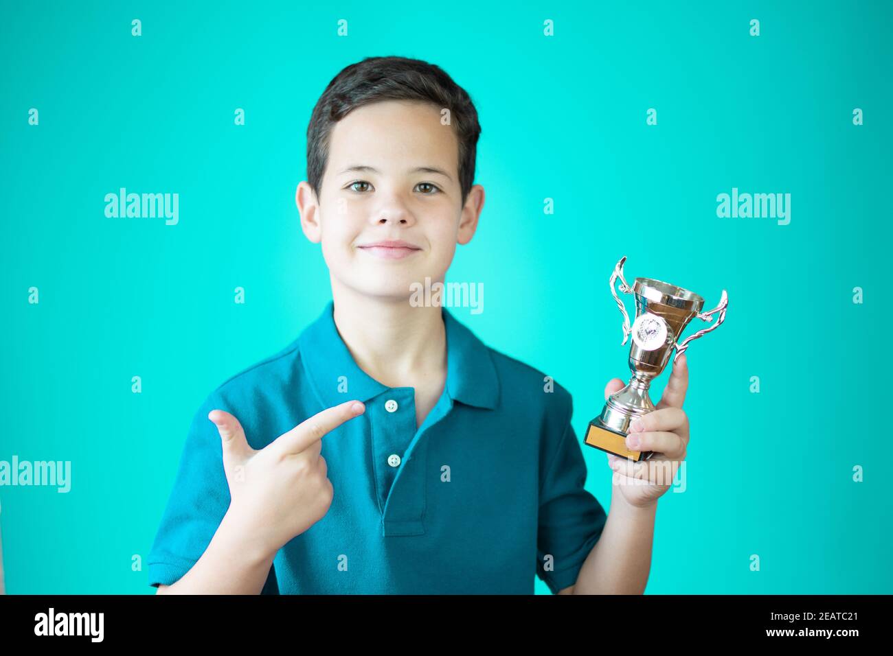 young boy holding a trophy with celebrating pose over green background ...