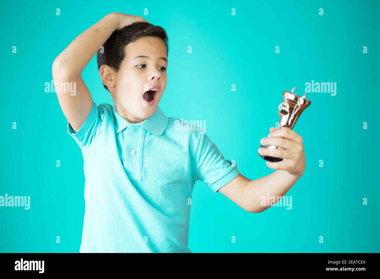 young boy holding a trophy with celebrating pose over green background ...