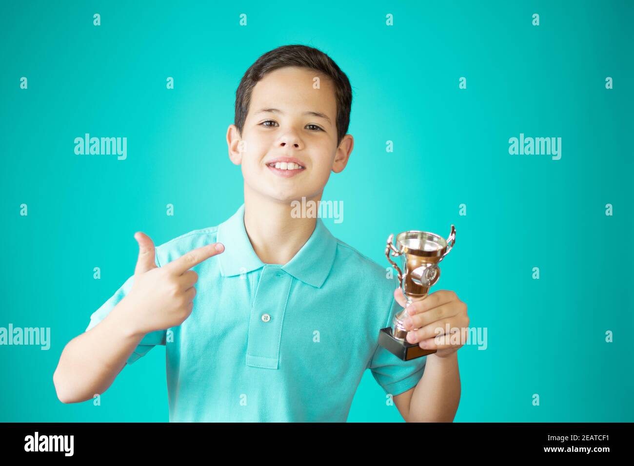 young boy holding a trophy with celebrating pose over green background ...