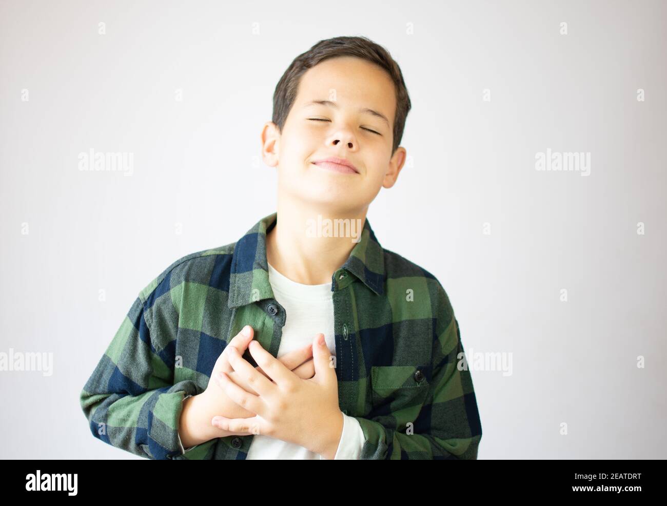 Beautiful smiling boy with hands on chest with closed eyes and grateful ...