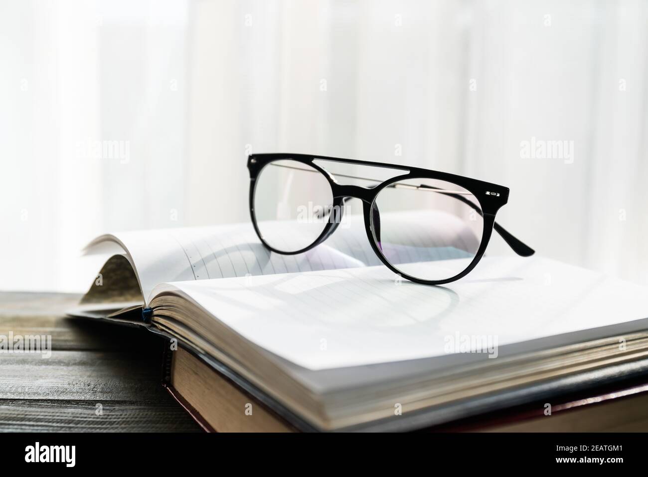 Reading glasses put on open book beside the window Stock Photo - Alamy