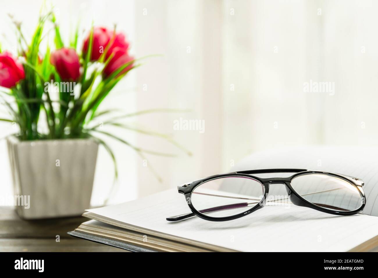 Reading glasses put on hardcover book beside the window Stock Photo - Alamy