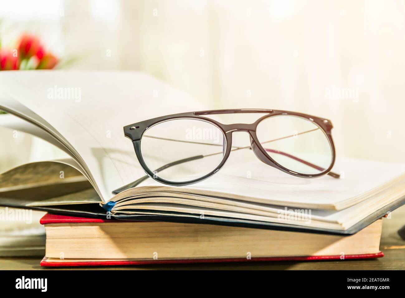 Reading glasses put on open book beside the window Stock Photo - Alamy