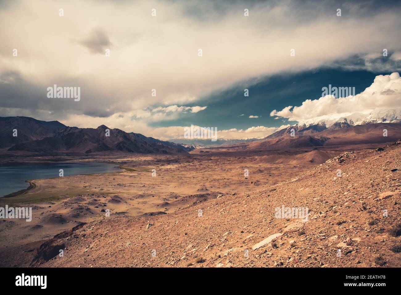 Remote empty valley with clouded mountain peaks in distance Stock Photo ...