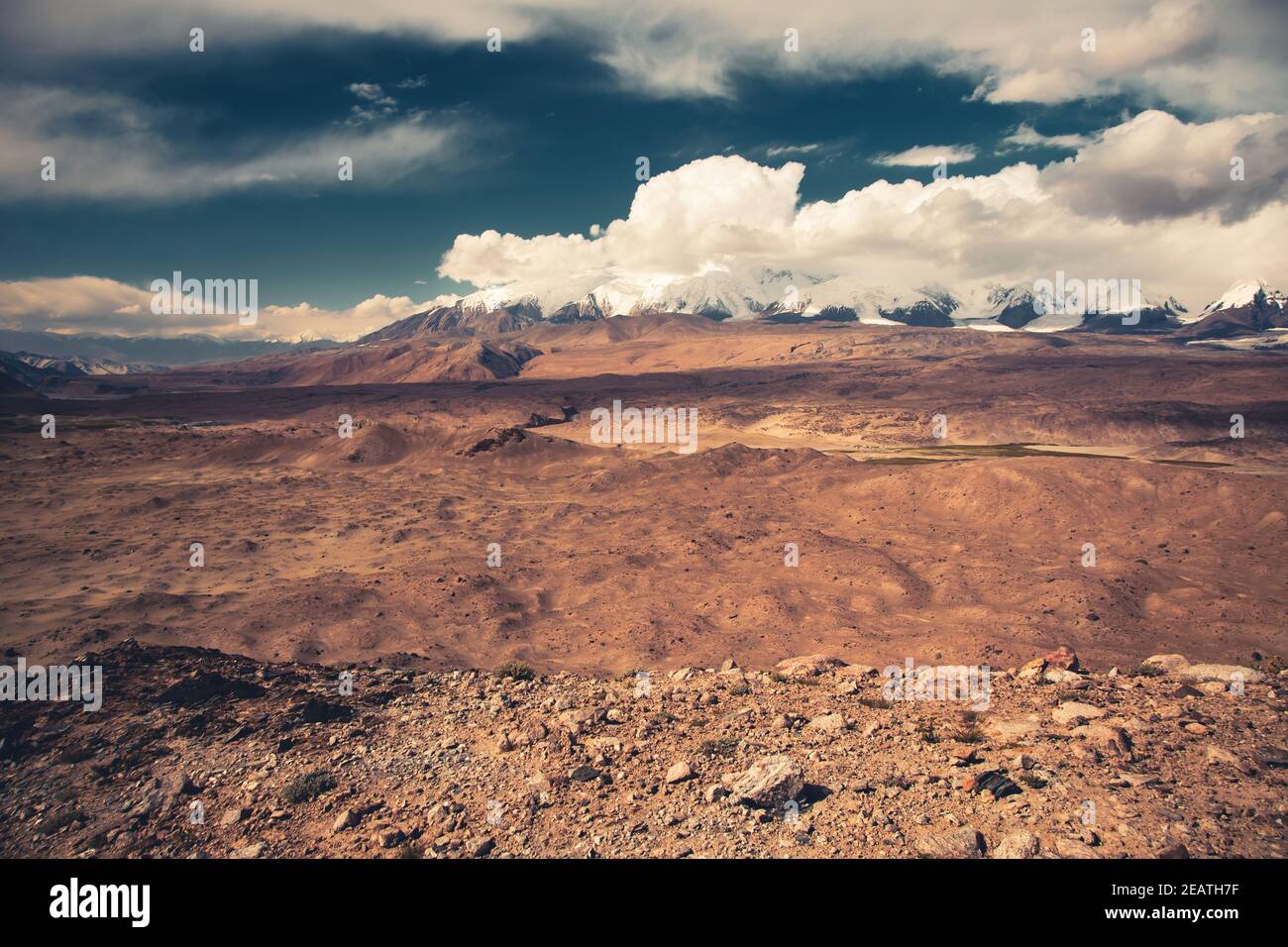 Remote empty valley with clouded mountain peaks in distance Stock Photo ...
