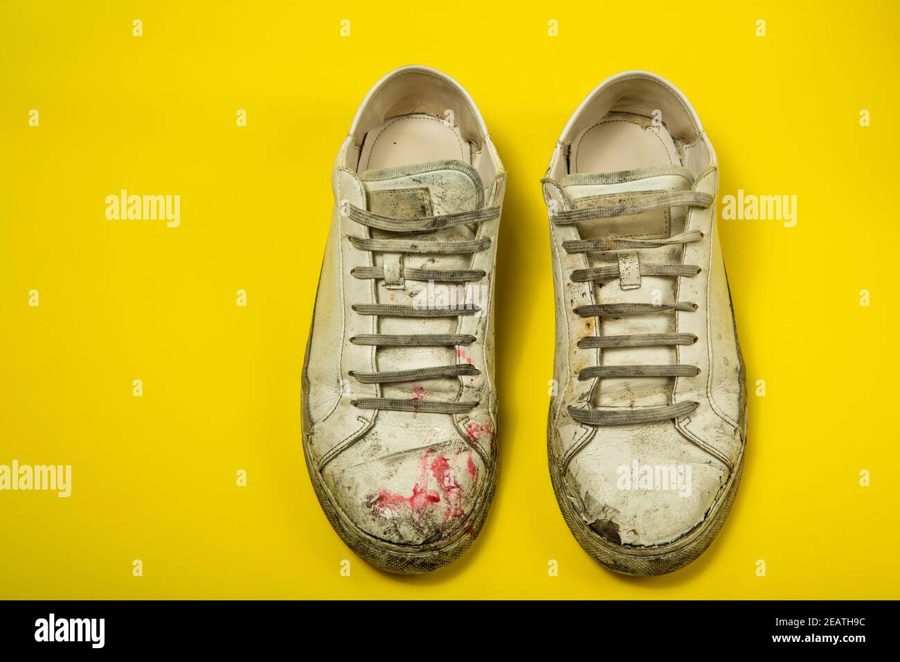 Dirty shoes, vintage white torn sneakers isolated on a yellow ...