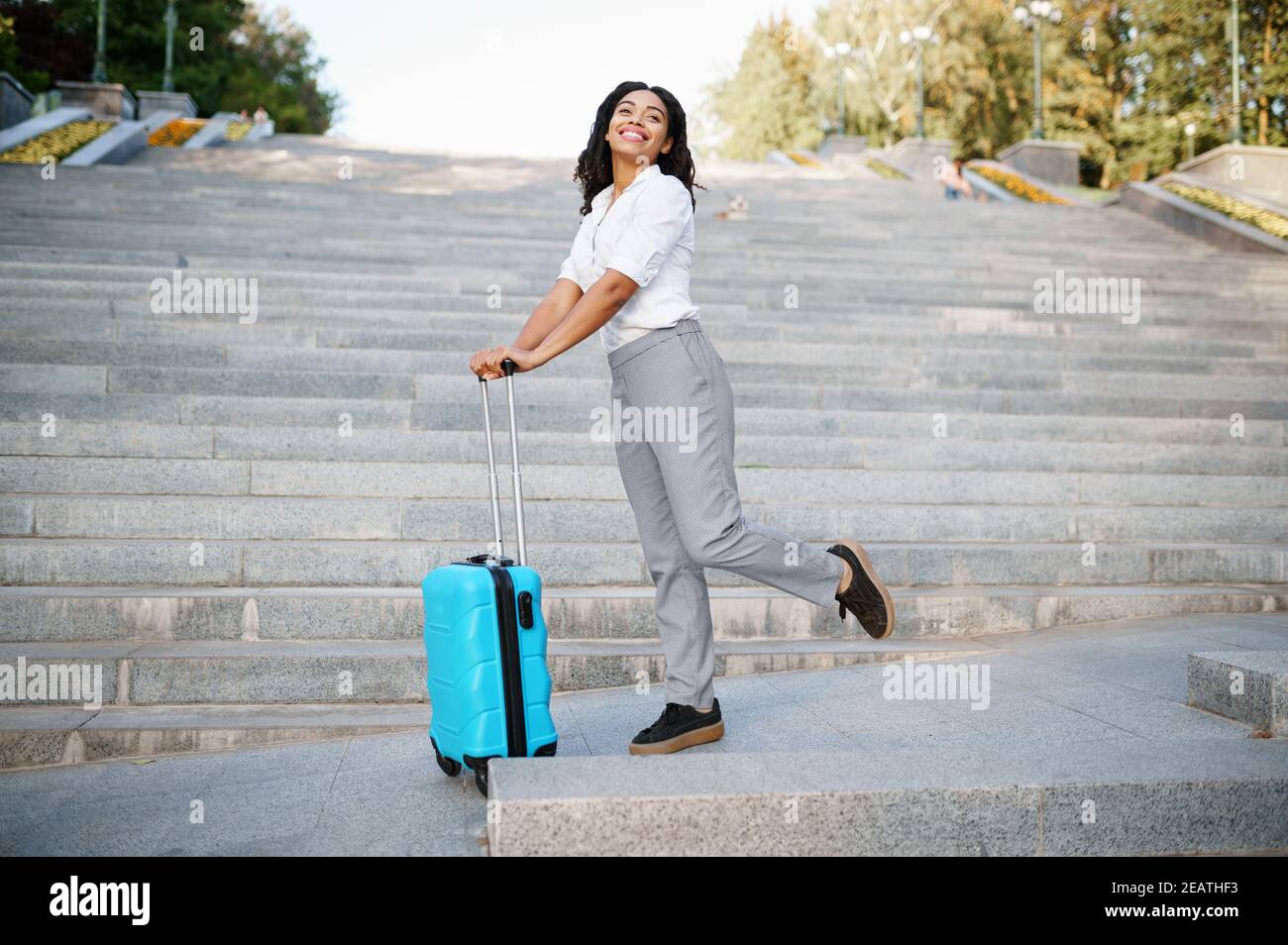 Woman poses with suitcase on the stairs in park Stock Photo - Alamy