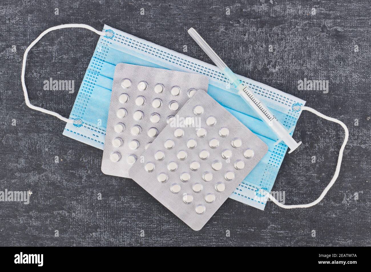 Pills, medical face mask, syringe on a gray background, top view. First ...