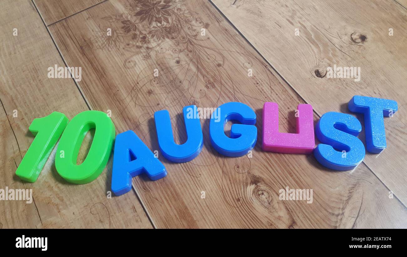 Plastic colored alphabets making words 10 August are placed on a wooden ...