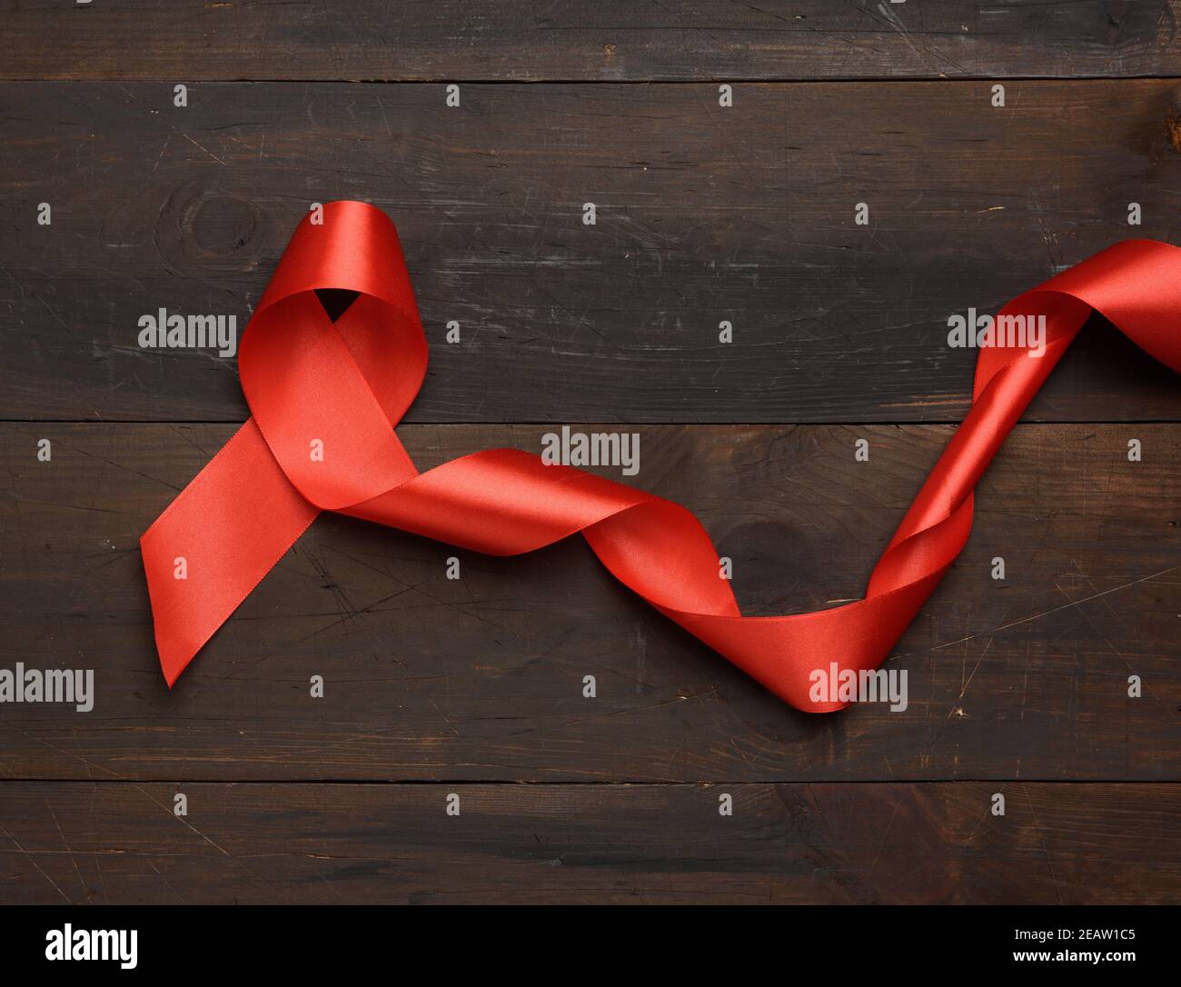 red silk ribbon folded into a loop on a brown wooden background Stock ...