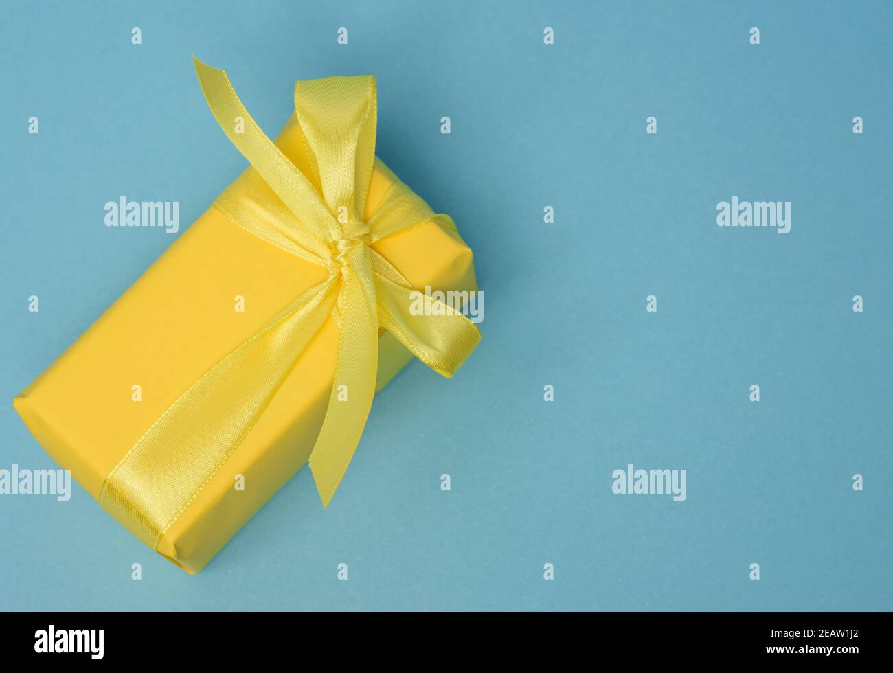 rectangular box with a gift wrapped in yellow paper and tied with a ...