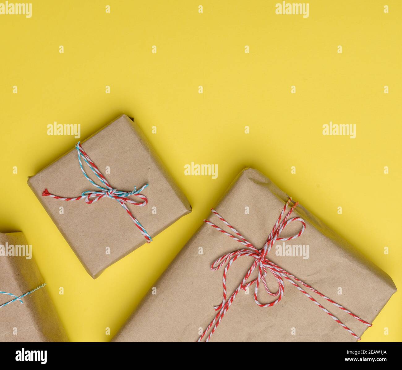 box wrapped in brown paper and tied with a rope, gift on a yellow ...