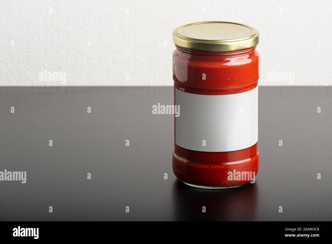 Tomato paste glassy jar with round cap on black table mock-up series ...