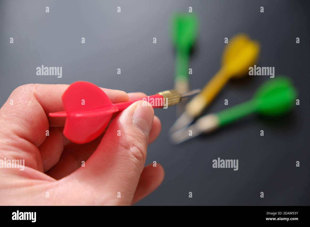 a hand throws darts on a dartboard, a hand holding a dart, a colorful ...