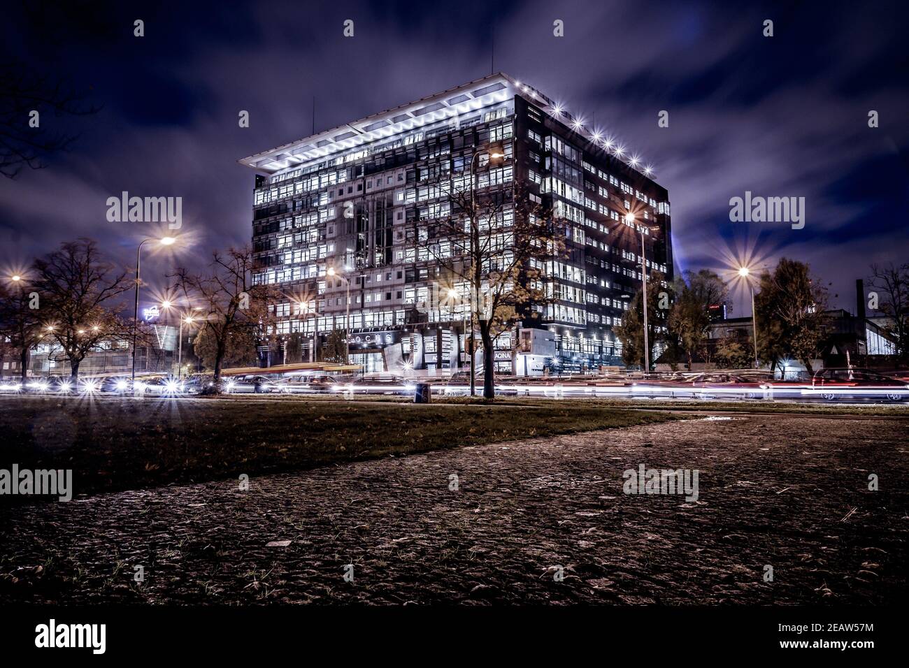Modern illuminated building in a city center surrounded by trees at ...