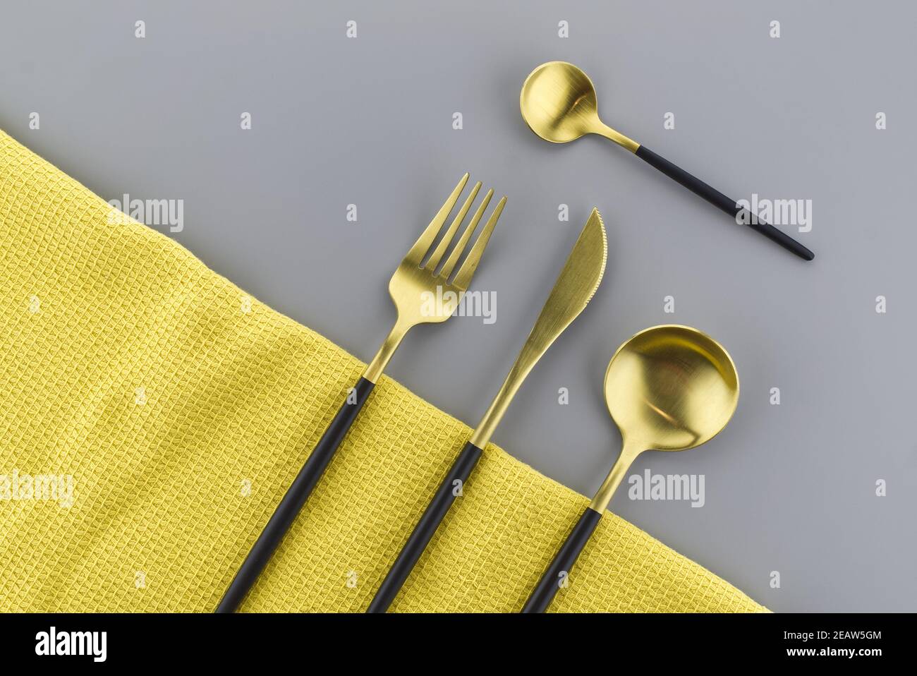 Black and gold cutlery on two tone grey and yellow Stock Photo - Alamy