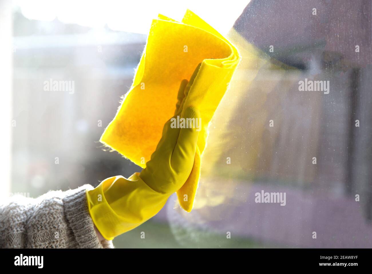 hand in yellow rubber glove holding yellow microfiber cleaning cloth ...