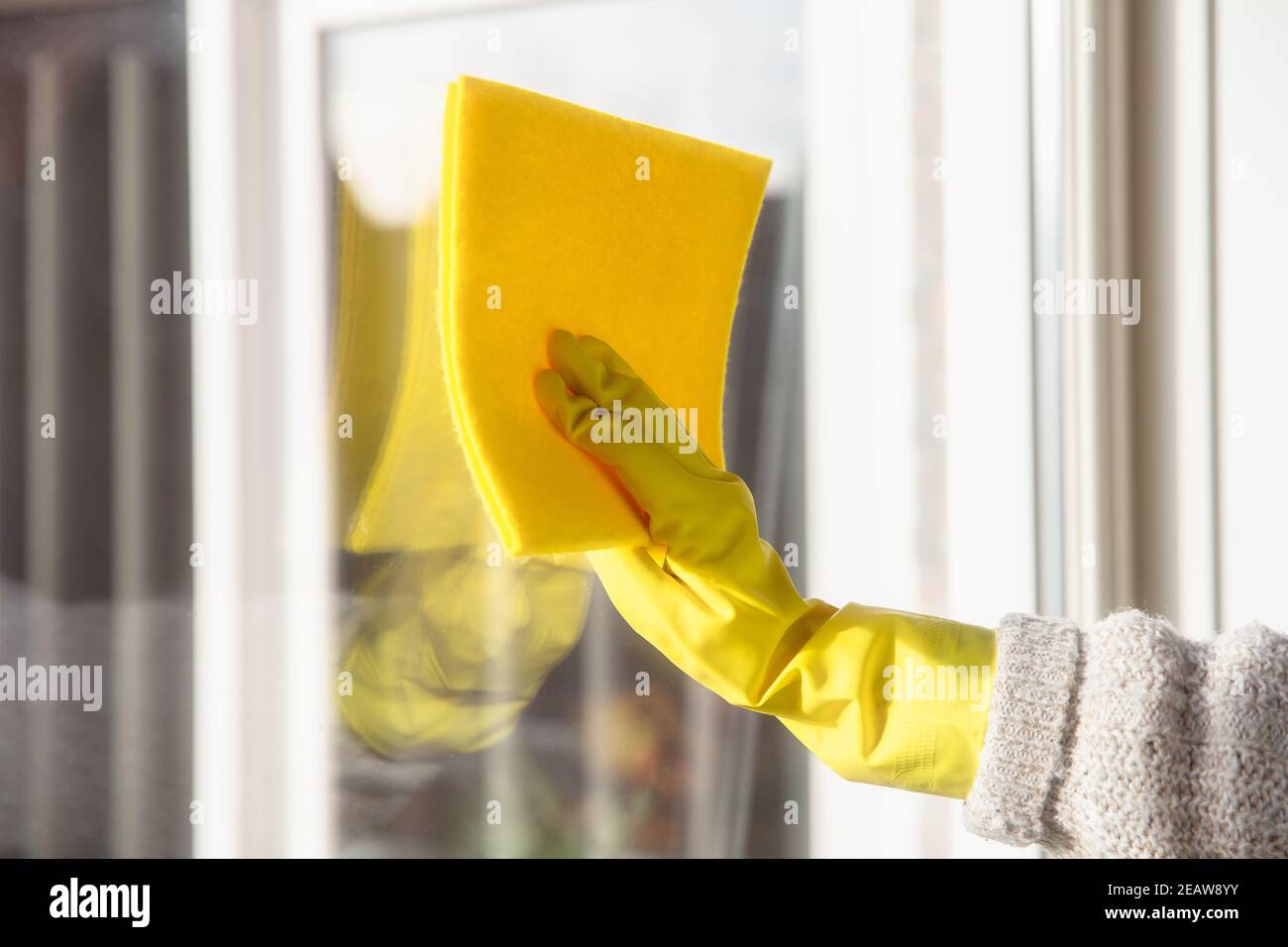 hand in yellow rubber glove holding yellow microfiber cleaning cloth ...