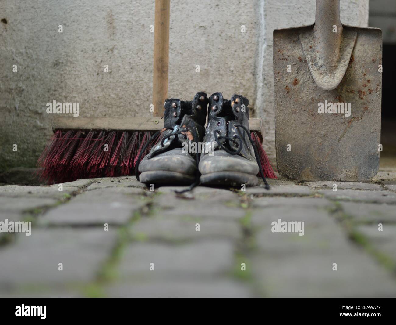 old worn painted work boots with a yard broom and a spade Stock Photo ...
