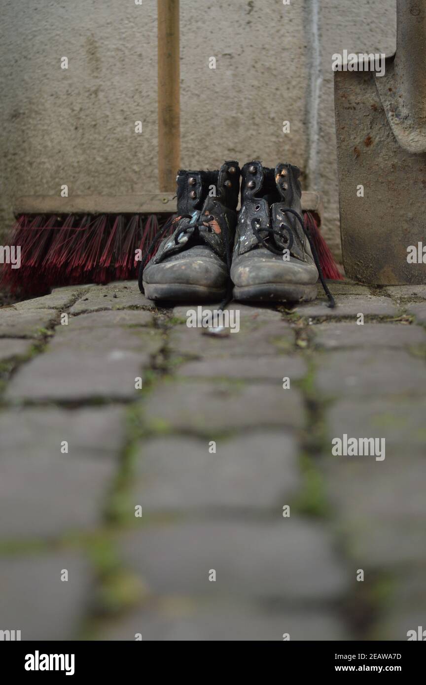 old worn painted work boots with a yard broom and a spade Stock Photo ...