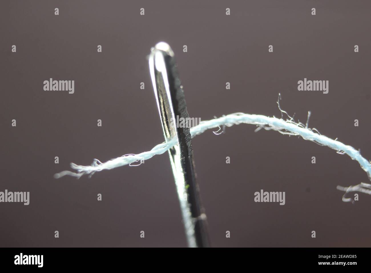 Small needle with thread in the eyelet, isolated over the black ...