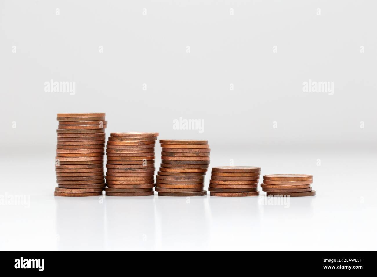Side view of stacks of coins increasing in height, on white studio ...
