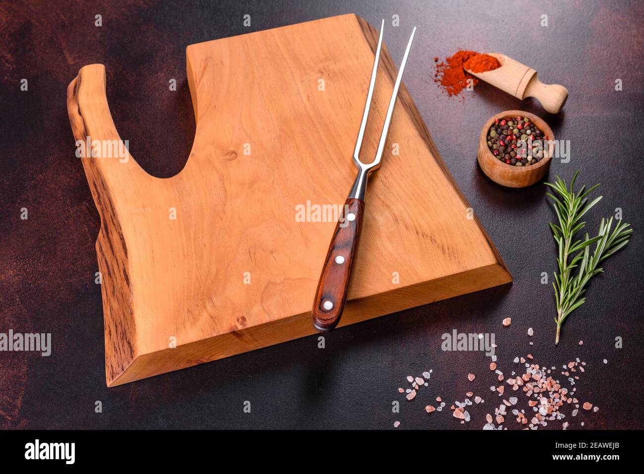 Cutting board with salt, spices and herbs on a dark concrete background ...