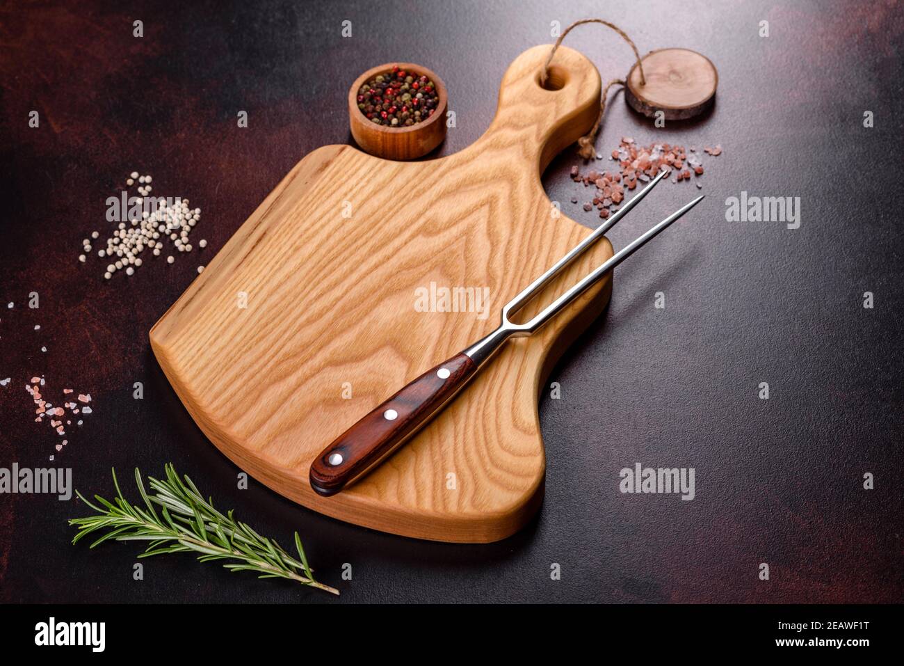 Cutting board with salt, spices and herbs on a dark concrete background ...