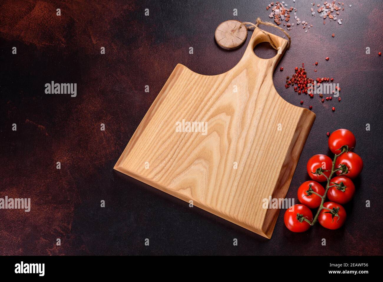 Cutting board with salt, spices and herbs on a dark concrete background ...