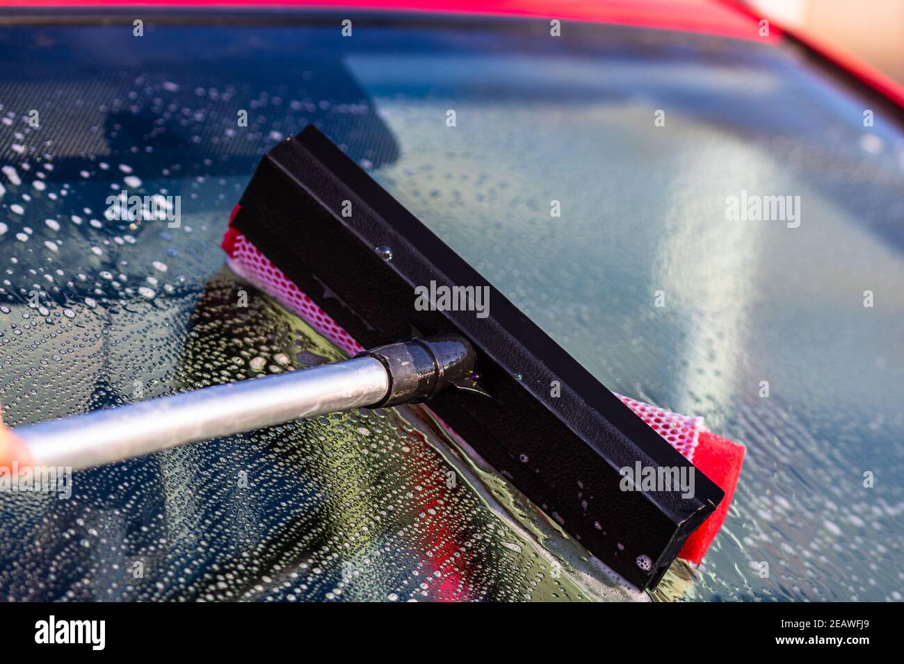 Washing and cleaning the front window of a car with mop in self service ...