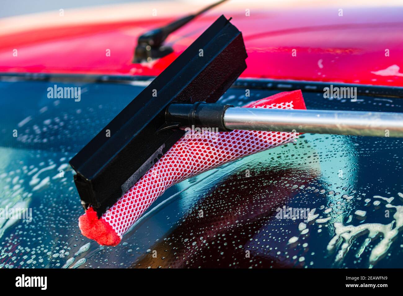 Washing and cleaning the front window of a car with mop in self service ...