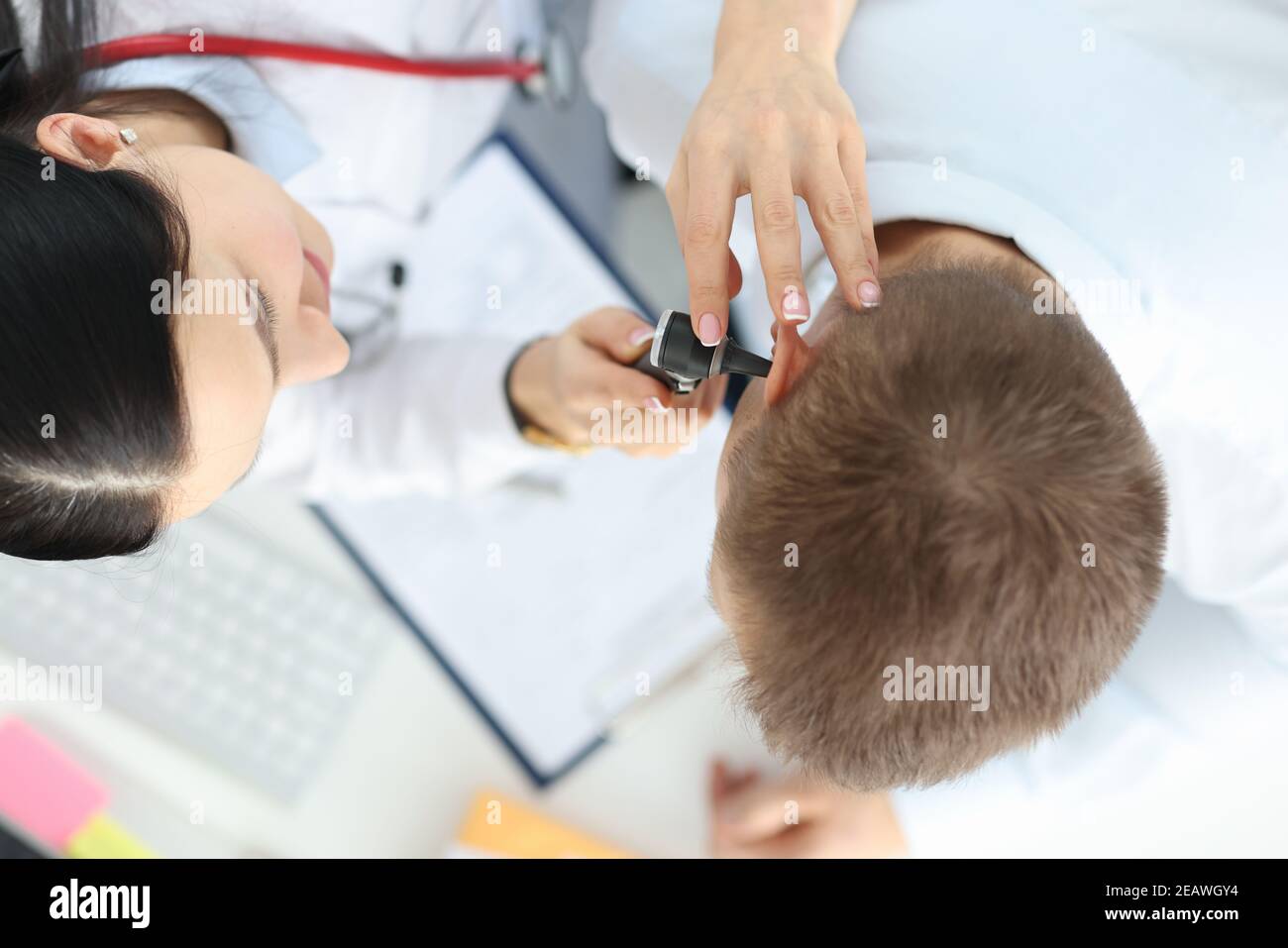 Otorhinolaryngologist examining patient with otoscope top view closeup ...