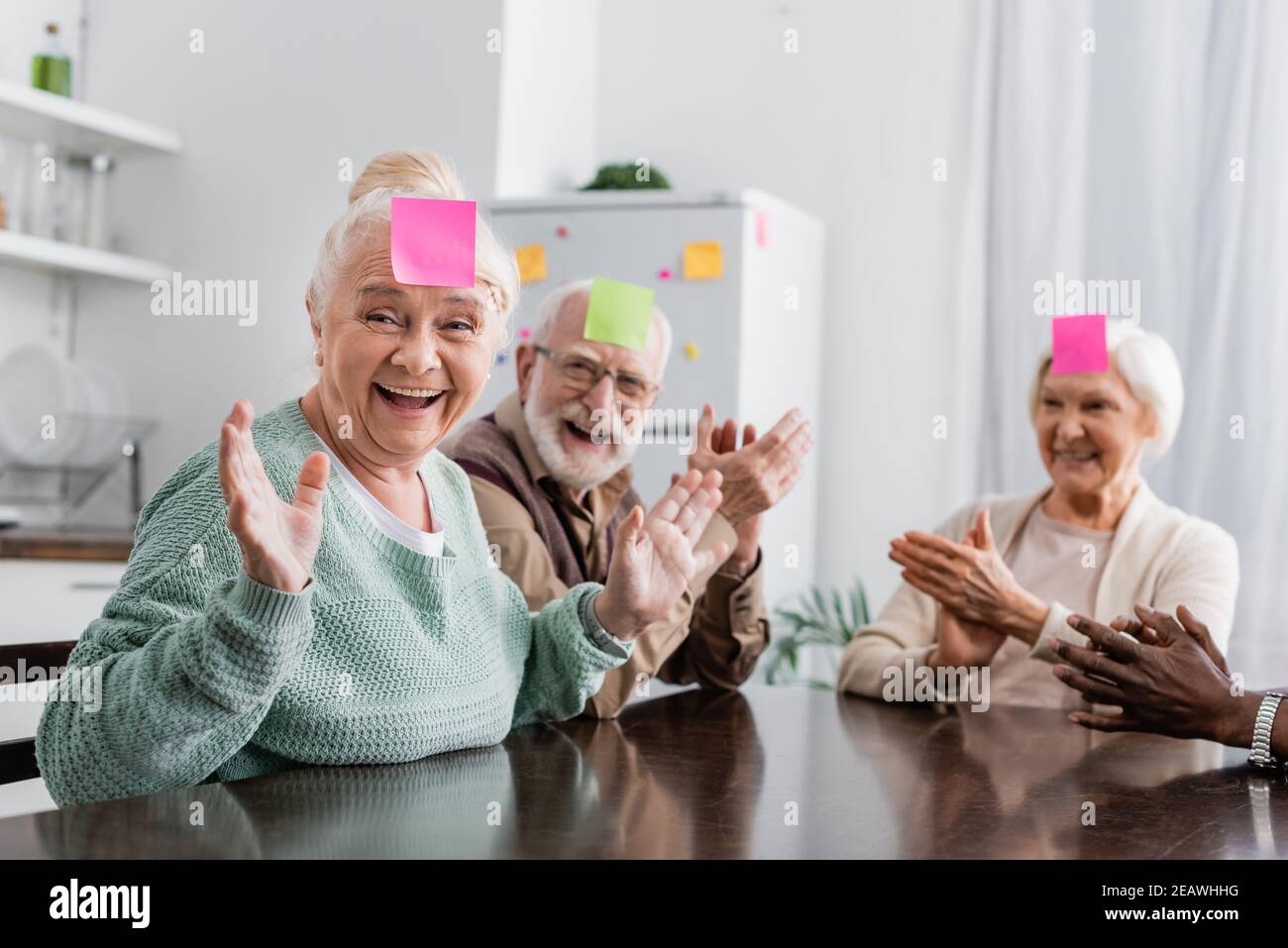 excited and multicultural senior friends with sticky notes on foreheads ...