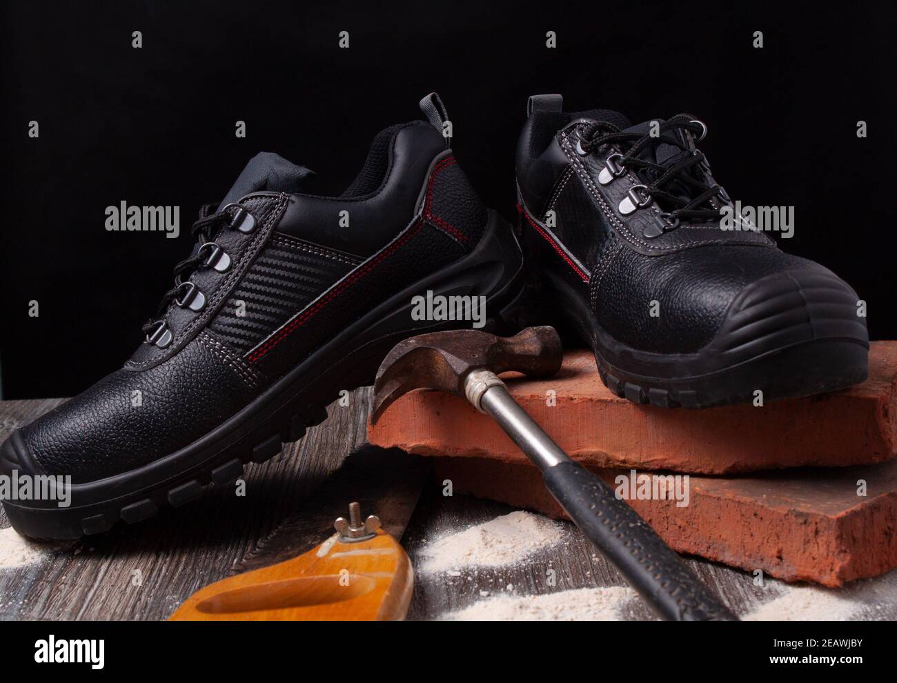 Still life of two safety shoes with a hammer and a saw for carpentry ...