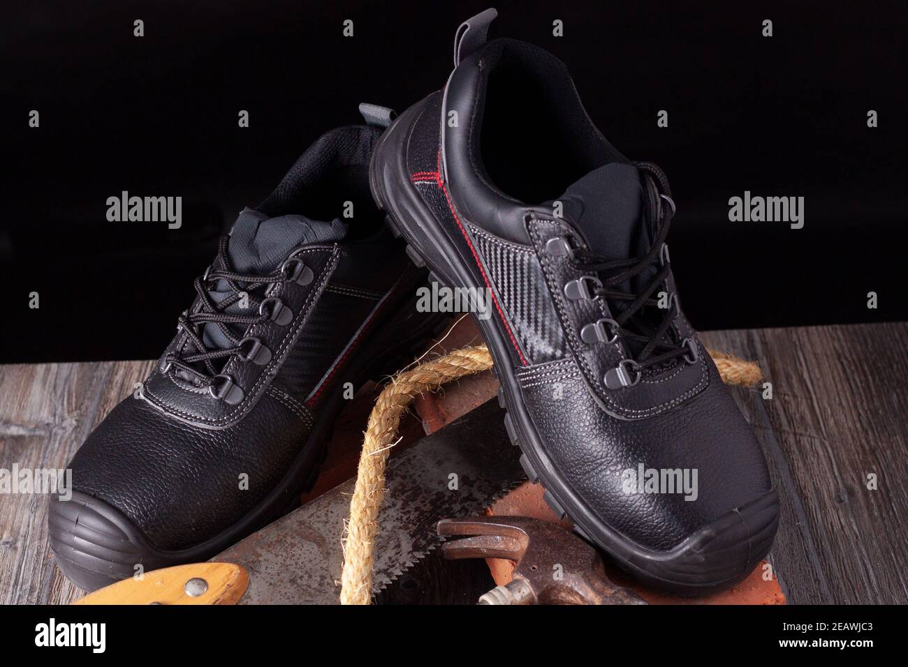 Still life of two safety shoes with a hammer and a saw for carpentry ...