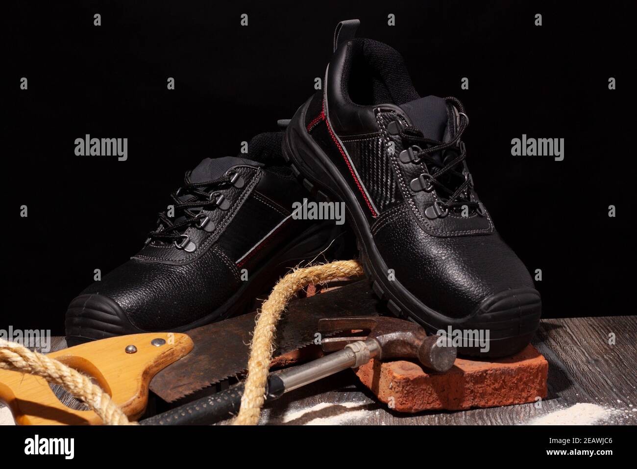 Still life of two safety shoes with a hammer and a saw for carpentry ...