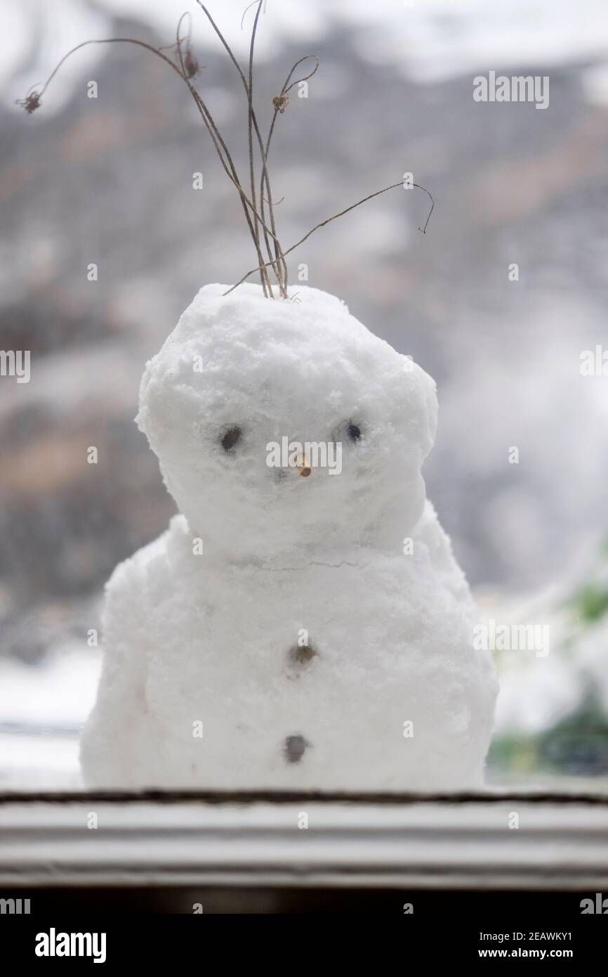 Small snowman on window ledge facing into house Stock Photo - Alamy
