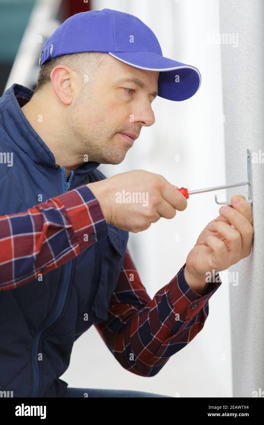 young smiling electrical technician is connecting a mechanism of socket ...
