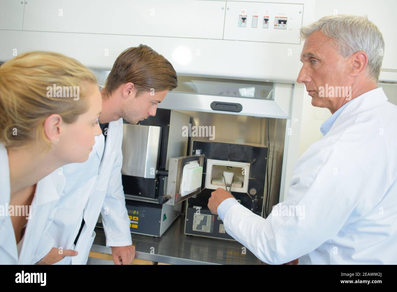 Man removing object with tongs, students watching Stock Photo - Alamy