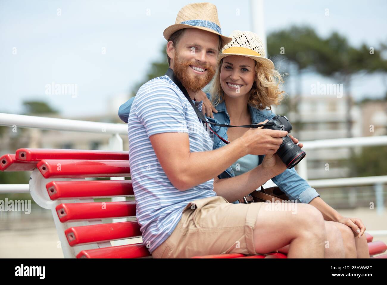 couple of tourists reviewing photos on camera sitting on bench Stock ...