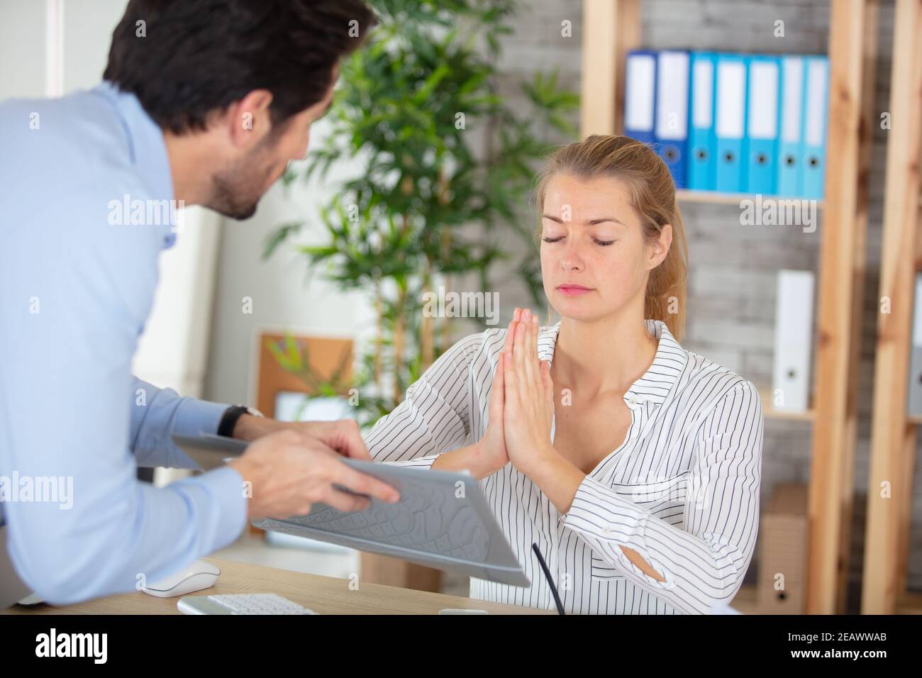 beautiful businesswoman meditating at workplace ignoring colleague ...