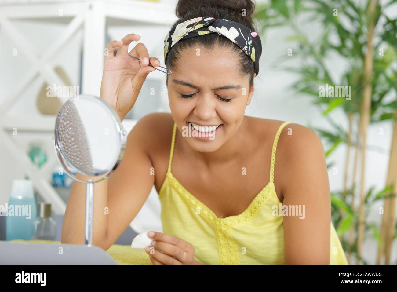 woman grimacing in pain as she uses tweezers on eyebrows Stock Photo ... woman grimacing in pain as she uses tweezers on eyebrows Stock Photo ...