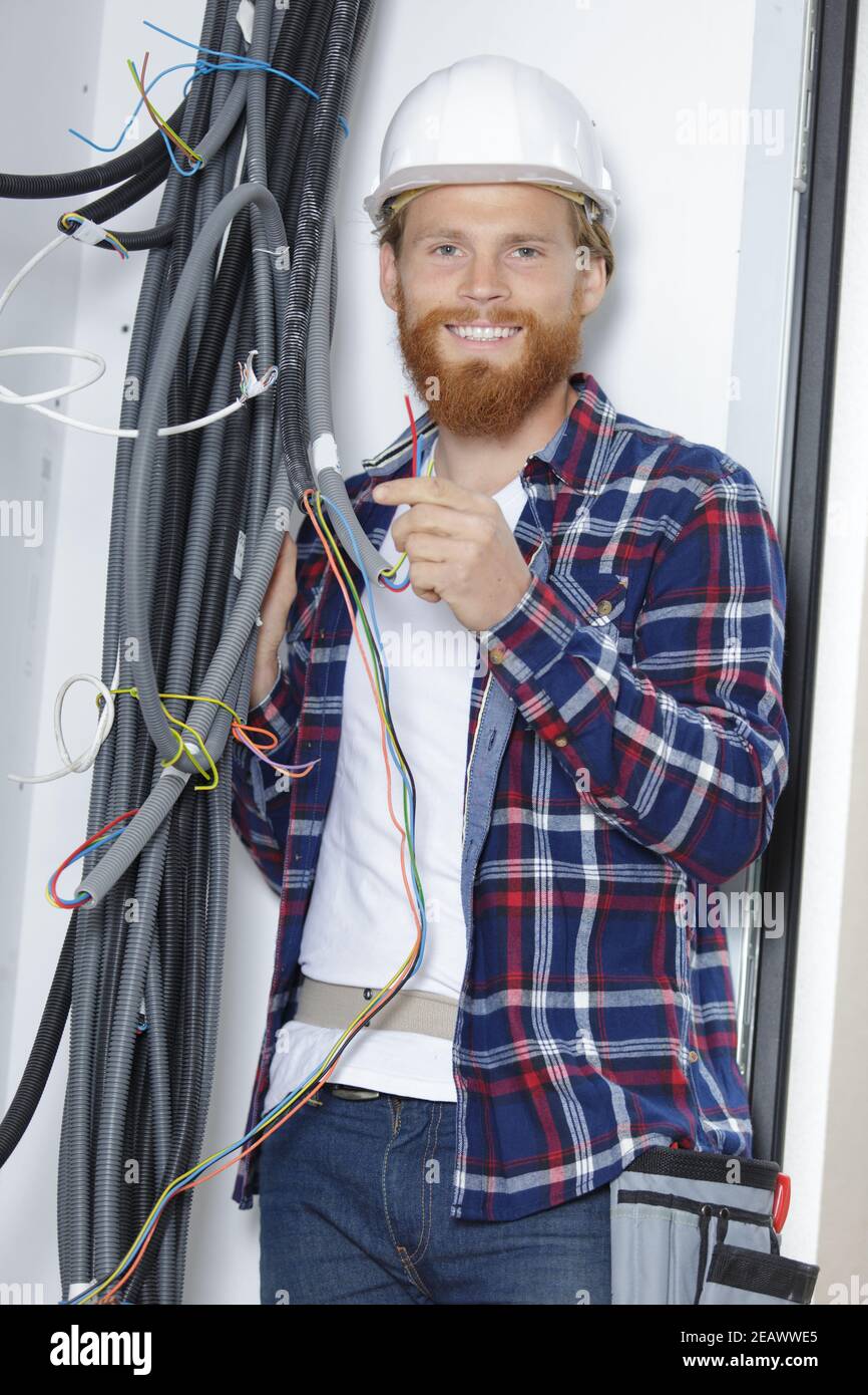 happy electrician in uniform with electric cable indoors Stock Photo ...