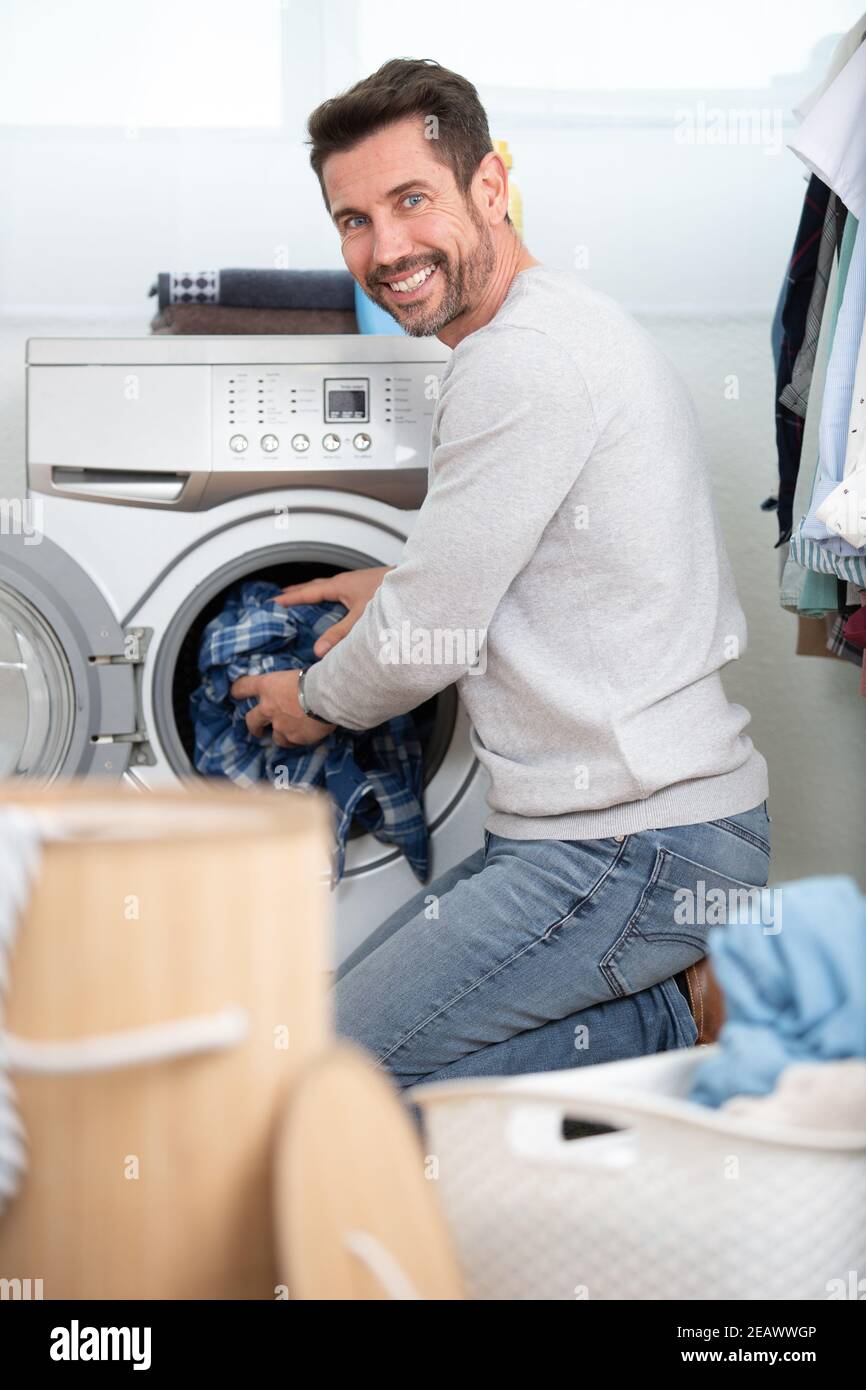 a smiling handsome man doing the laundry Stock Photo - Alamy