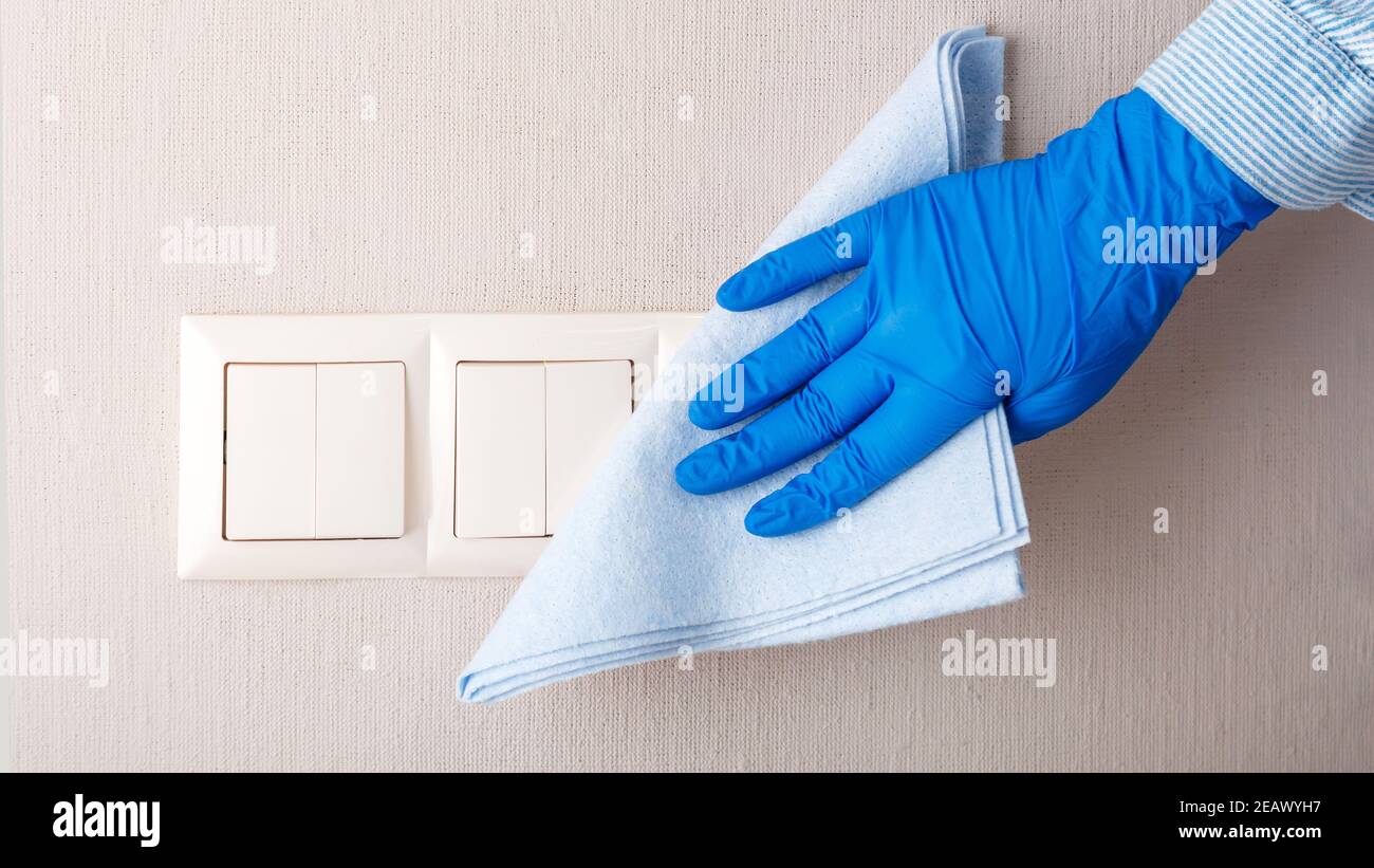 Light switch surfaces disinfection. Woman in rubber blue glove clean ...
