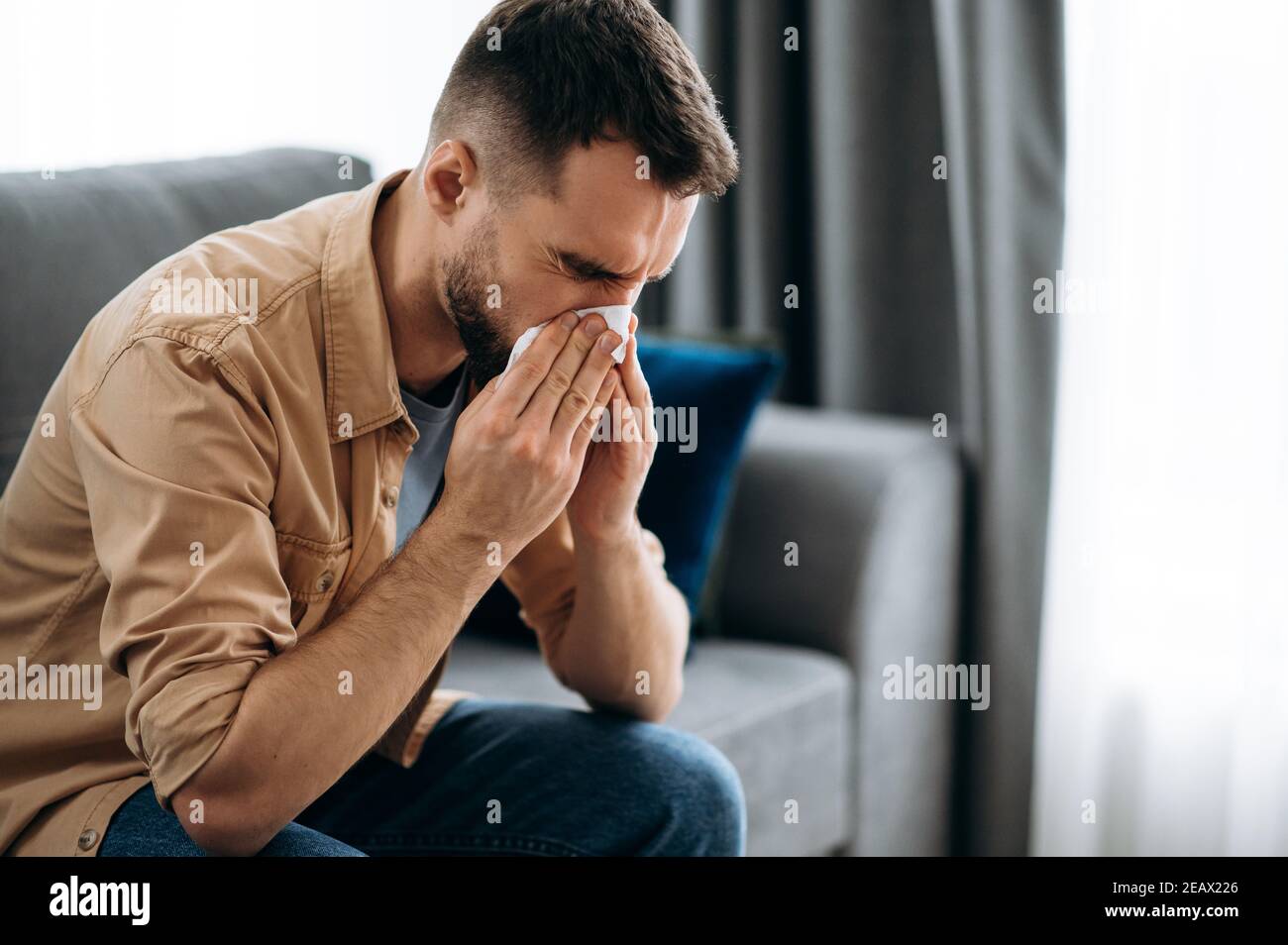 Sick caucasian guy sits on couch feel unhealthy, he suffering from ...