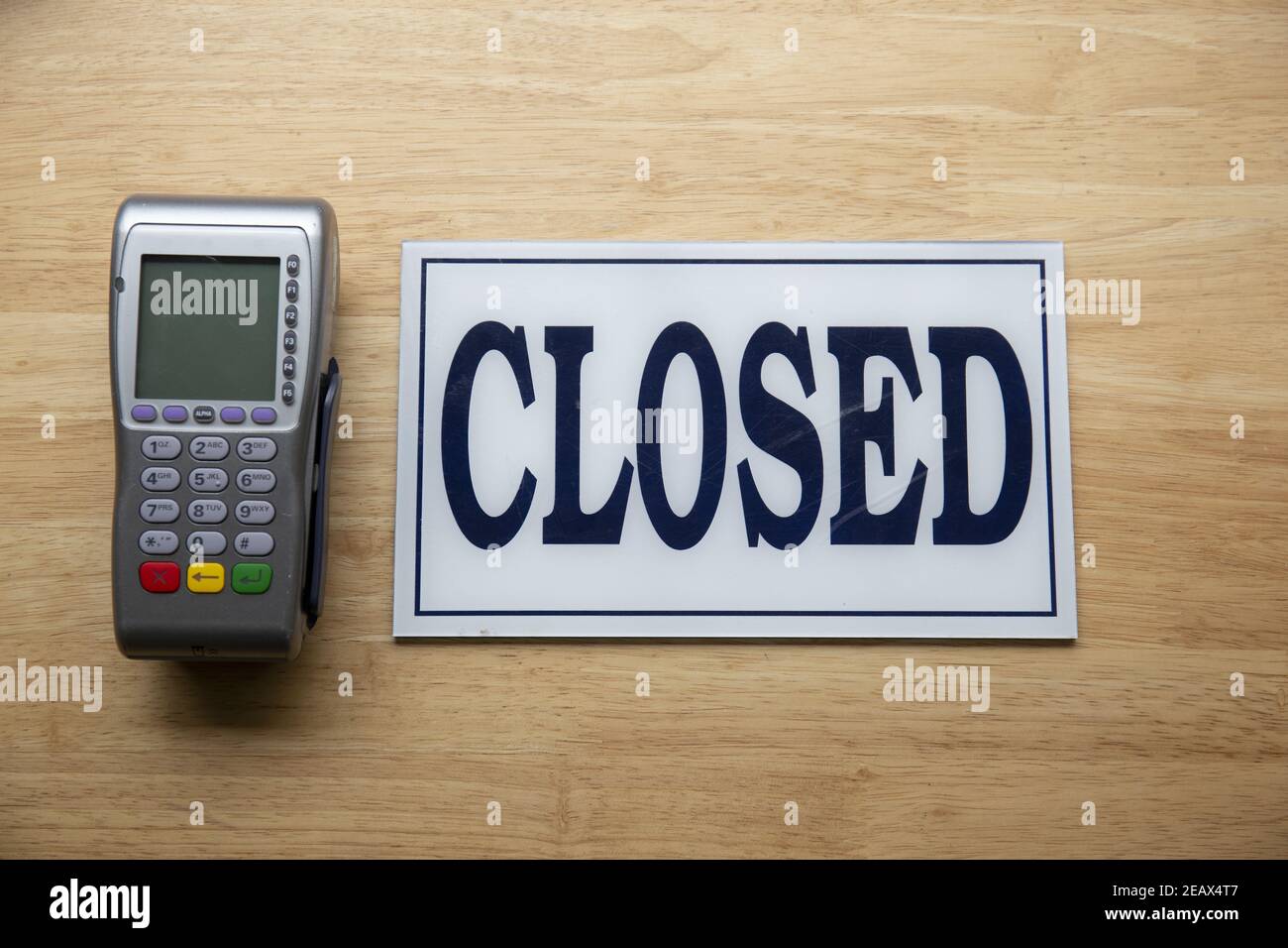 Card and cheque terminal and a sign "CLOSED" on a wooden table ...